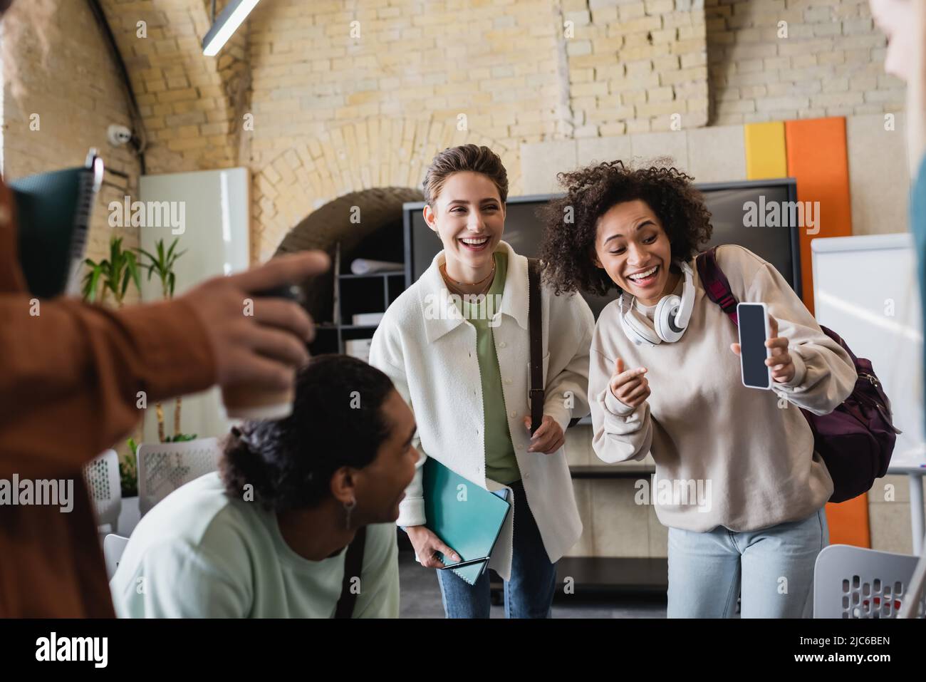 excited african american woman pointing at mobile phone near ...