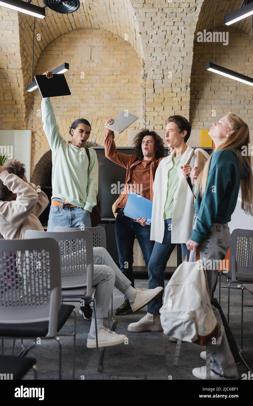 excited multiethnic students with closed eyes showing win gesture in ...