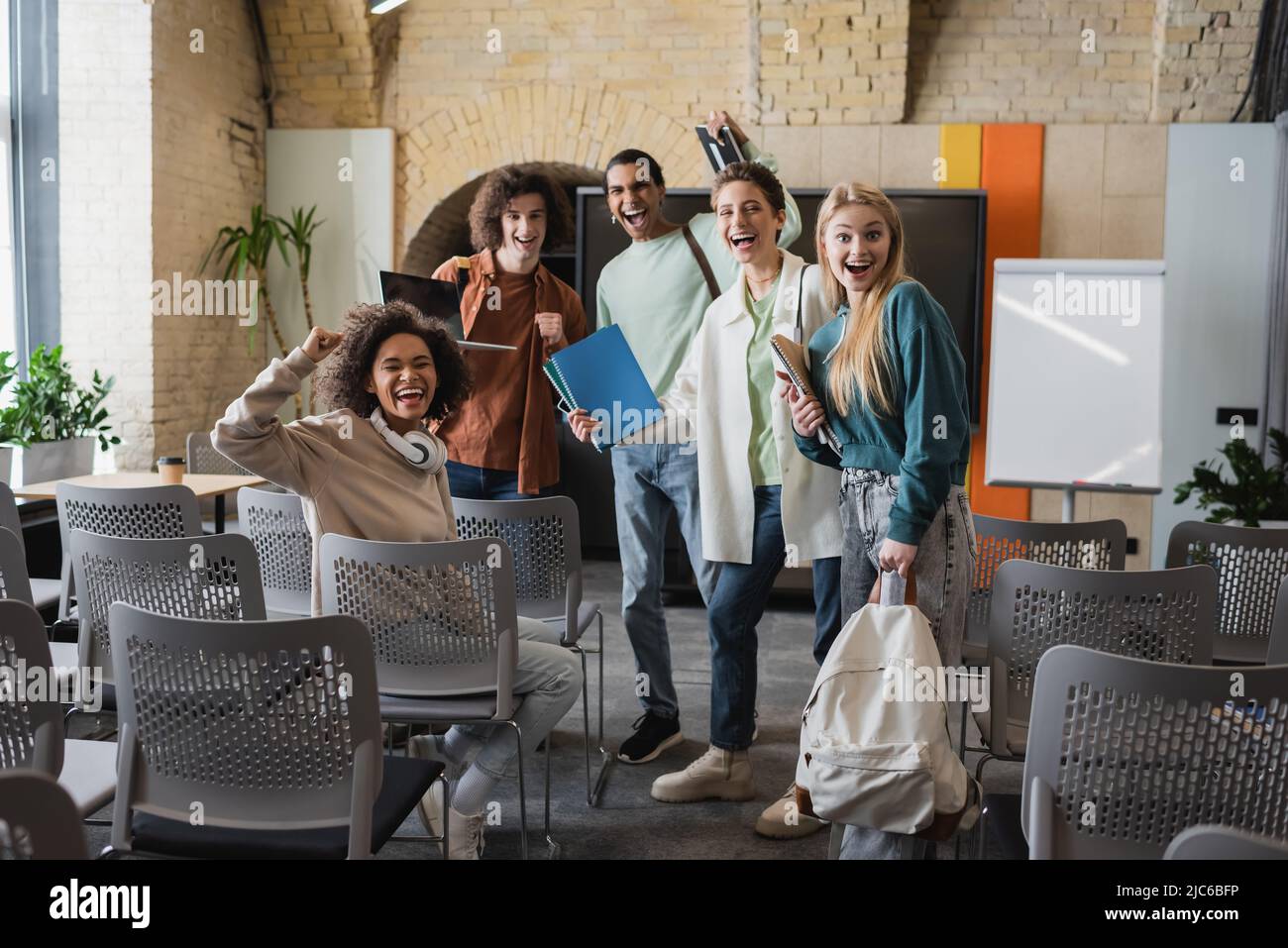 excited multiethnic classmates shouting and showing success gesture in ...