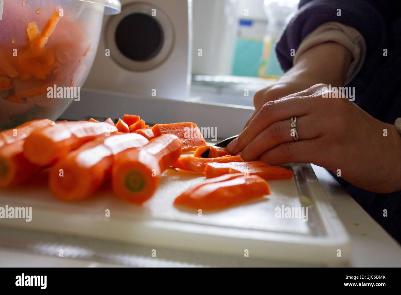 A portrait of a person chopping up carrots into small pieces on a ...