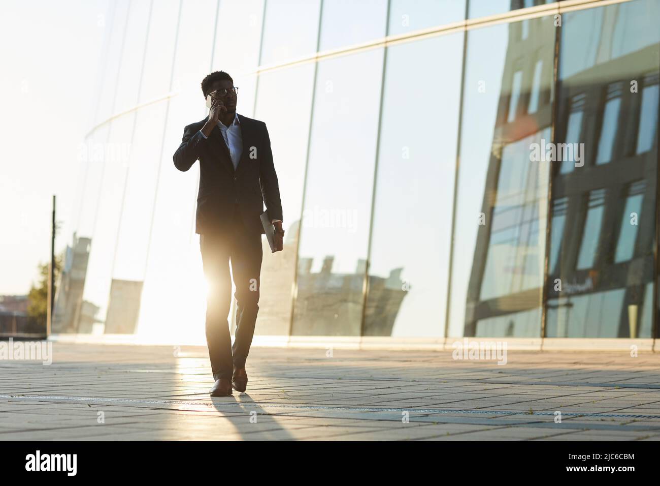Contemporary mobile black manager in suit walking over financial ...