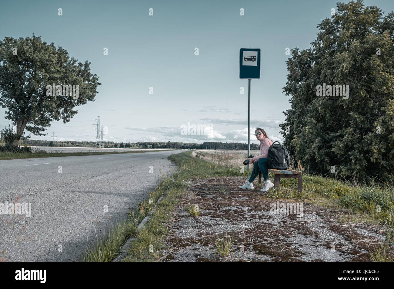 a woman sits on a bench at a city bus stop. Travel around the country ...
