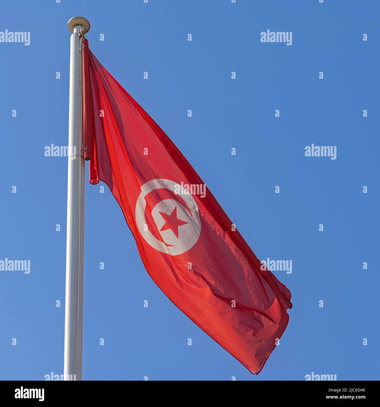 New Bright Red Flag of Tunisia at Clear Blue Sky Stock Photo - Alamy