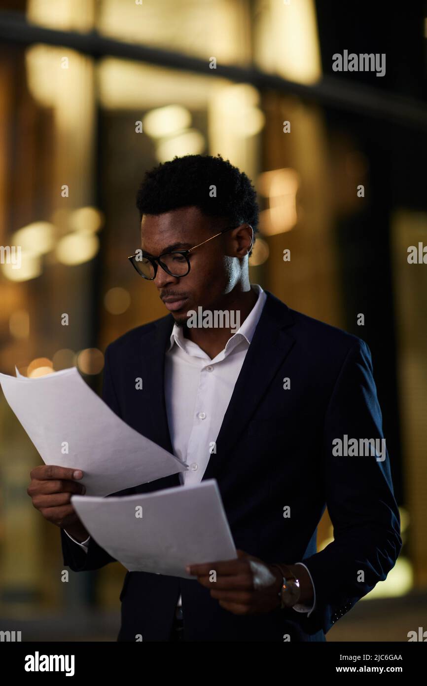 Busy young black male manager in suit concentrated on contract content ...