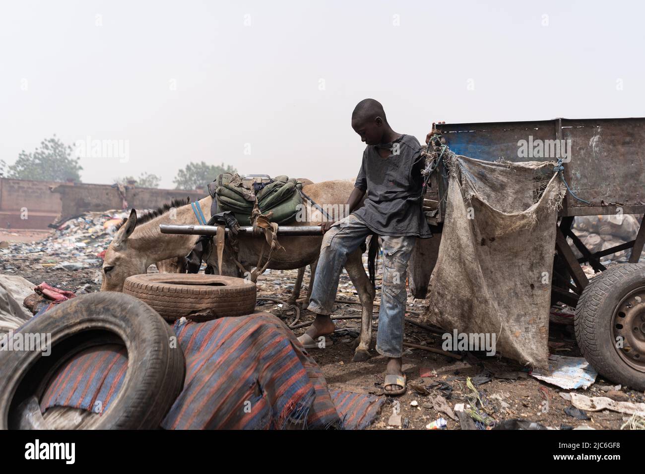Hopeless African young boy sitting alone on a handcart with a donkey ...