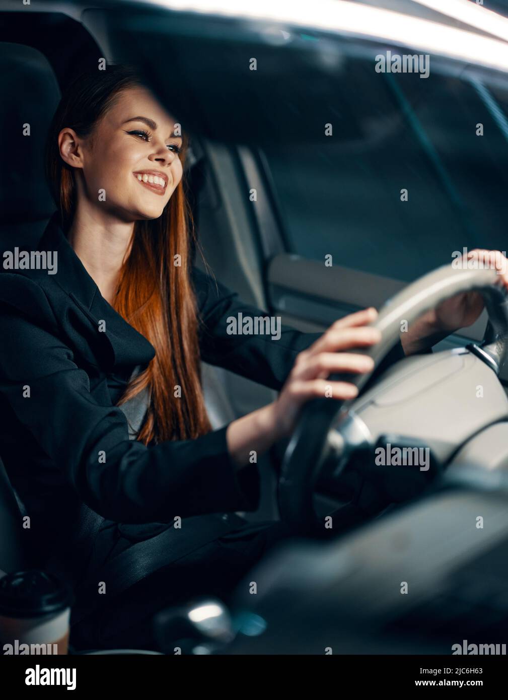 vertical photo of a pleasant, relaxed woman sitting behind the wheel of ...