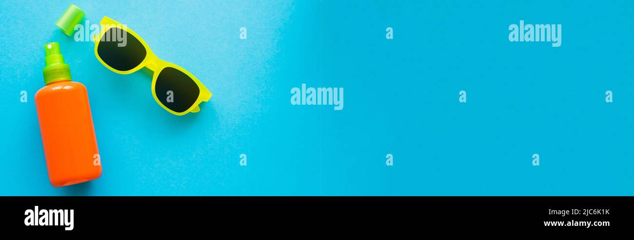 Top view of bottle of sunblock and sunglasses on blue background ...
