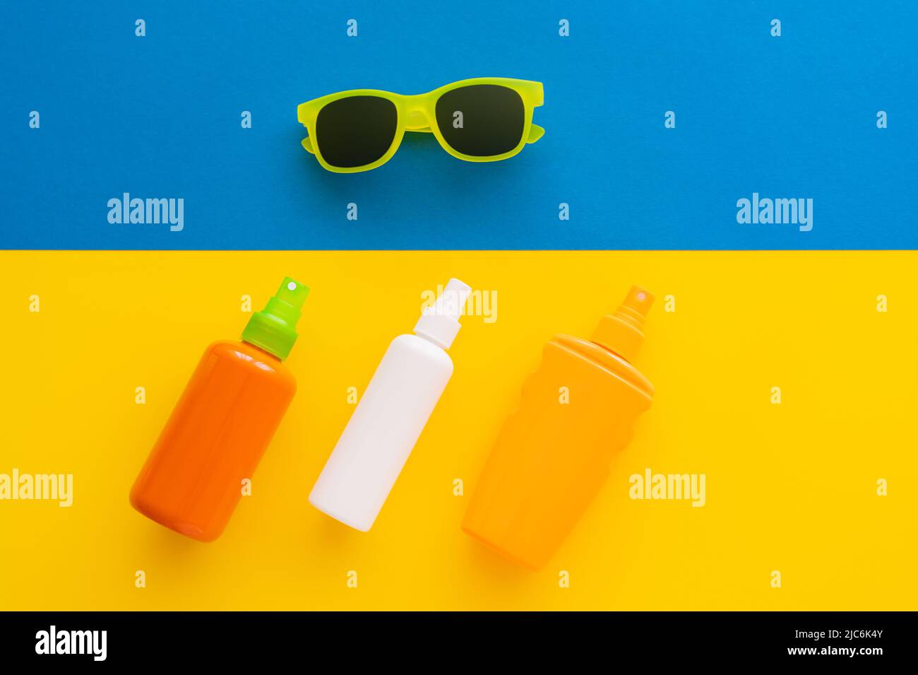 Top view of sunblocks and sunglasses on yellow and blue background ...