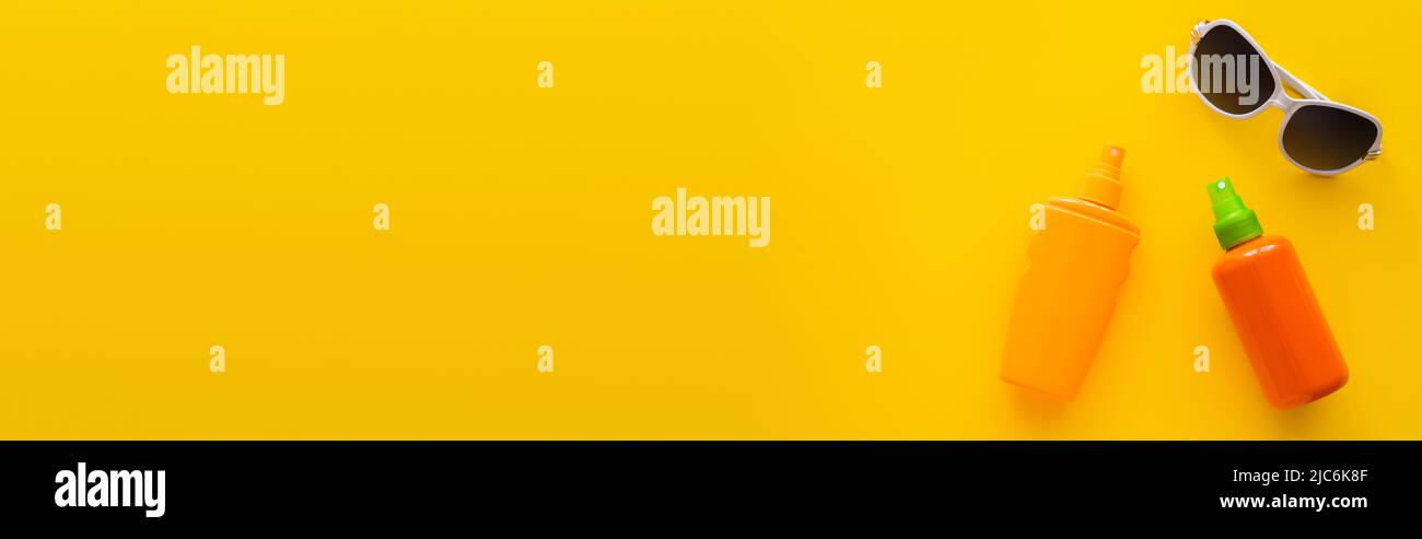 Top view of sunglasses and sunscreens on yellow background, banner ...