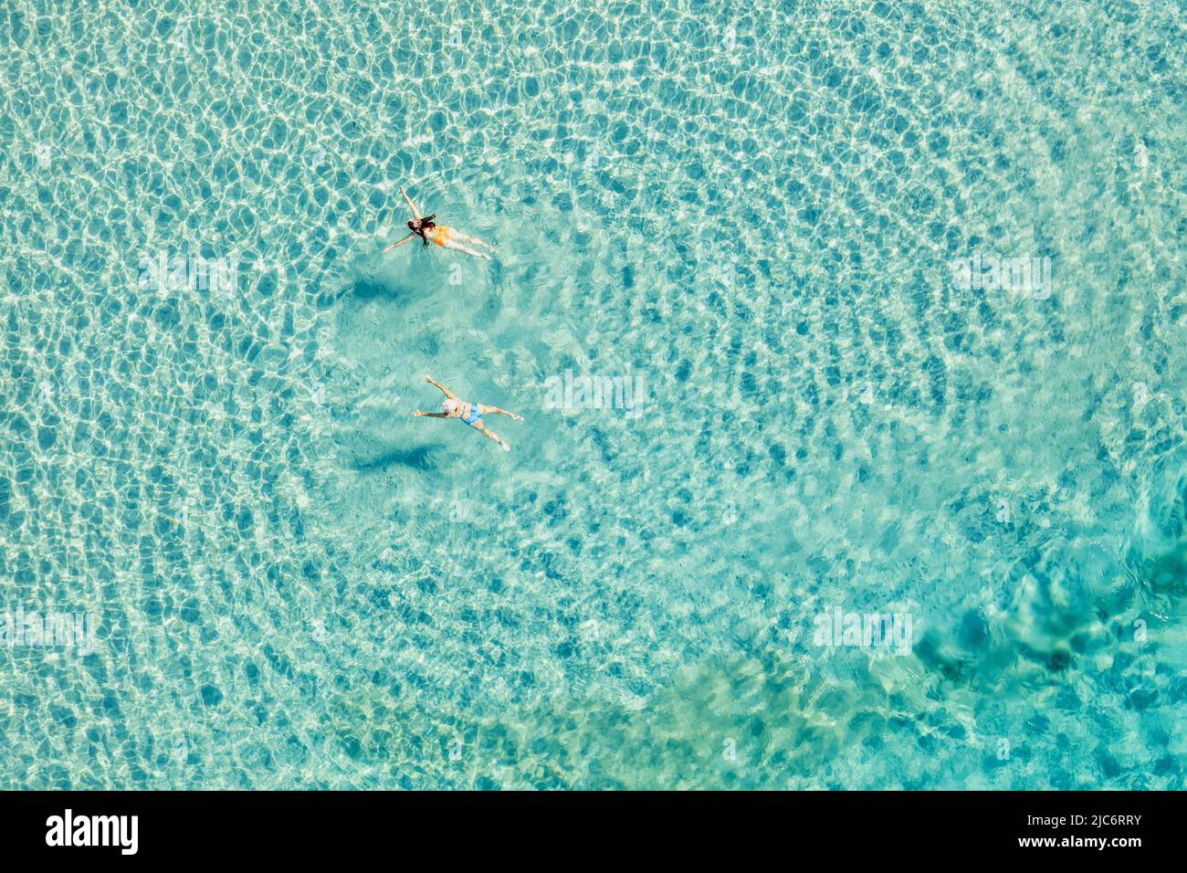 Women swim in transparent turquoise blue sea water aerial drone view ...