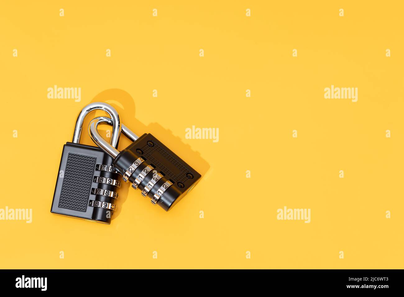 Two padlocks linked together isolated on yellow background. Copy space ...