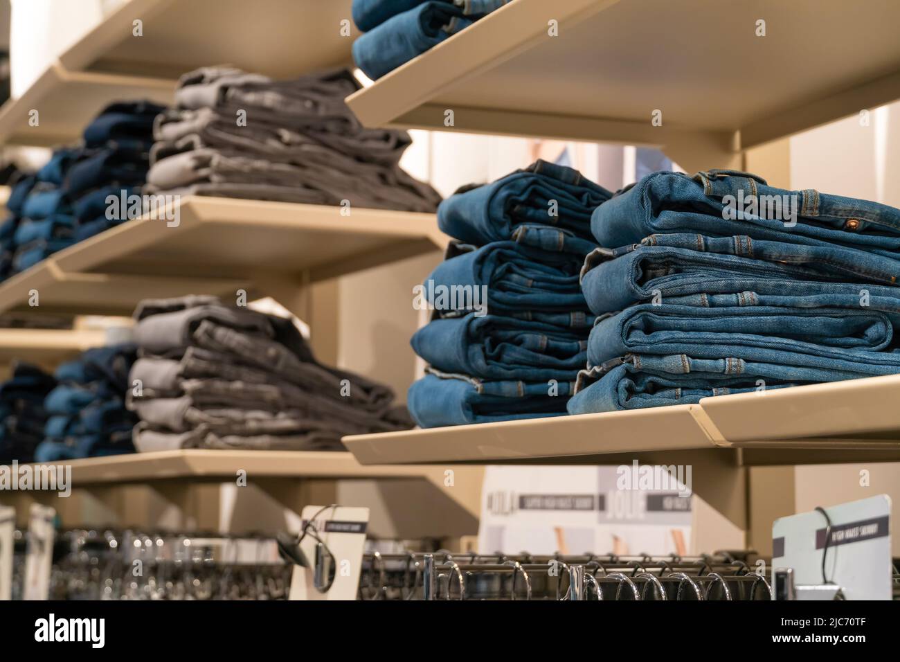 Stacks of jeans on a shelf in a mall store. Concept of buying, selling ...