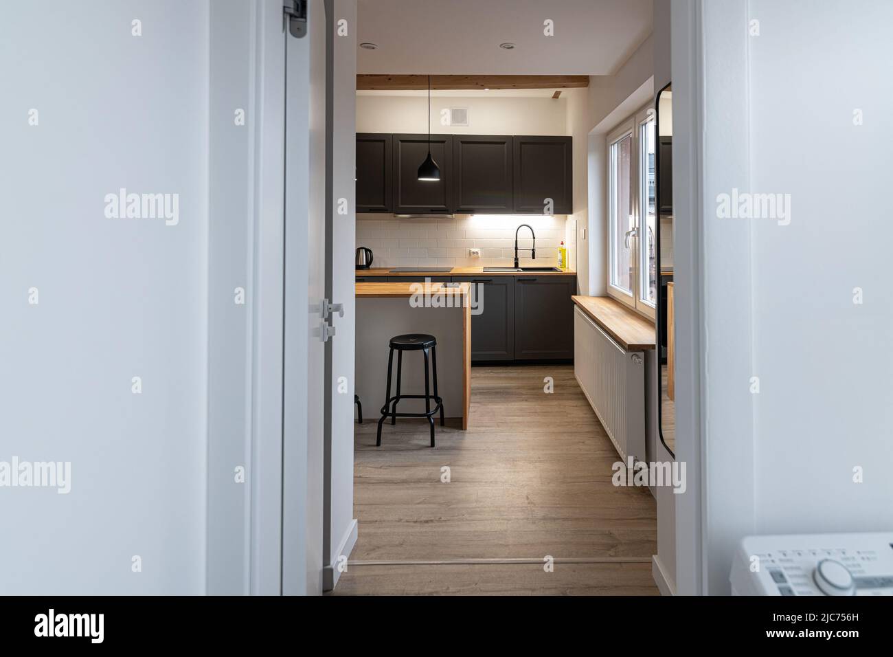 View from the hall to a modern kitchen with black kitchen cabinets ...