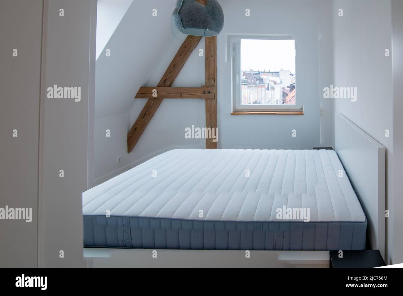 Empty mattress on the bed in a small bedroom with a window Stock Photo ...
