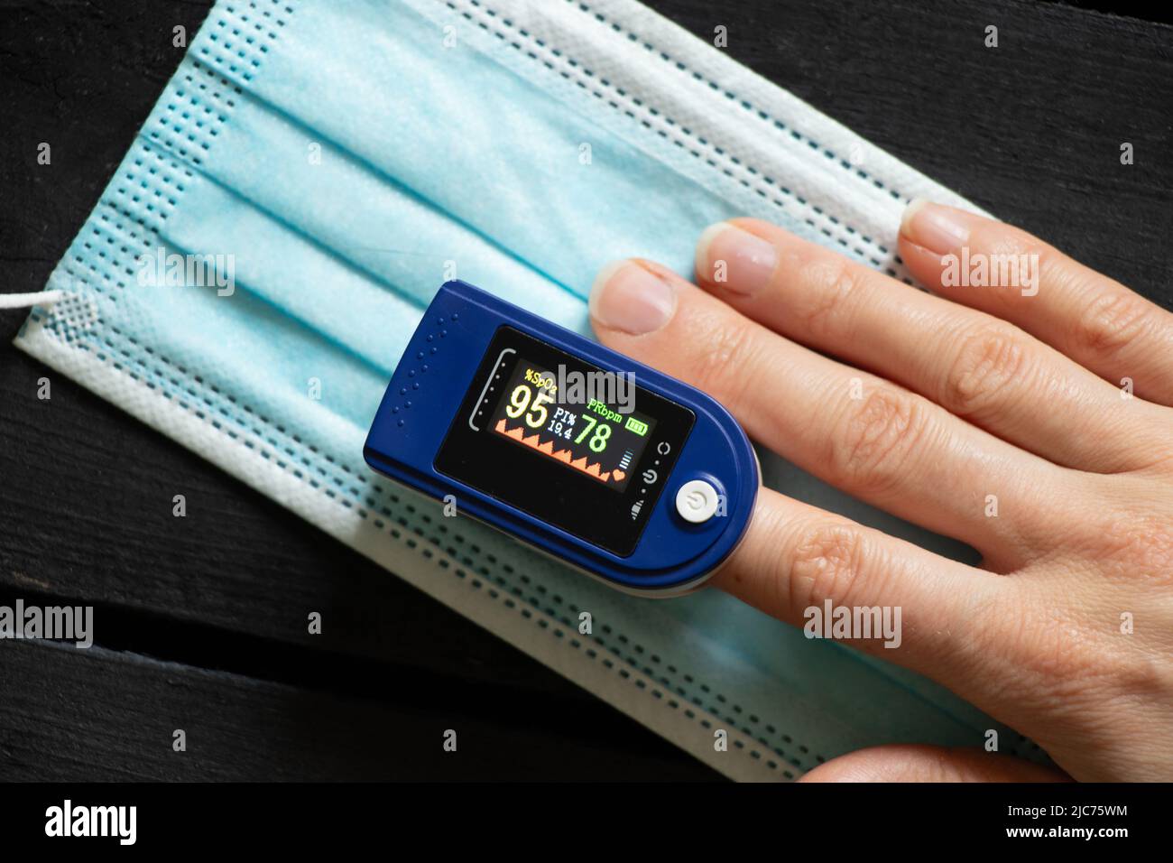 woman's finger pulse oximeter and disposable medical mask on isolated ...