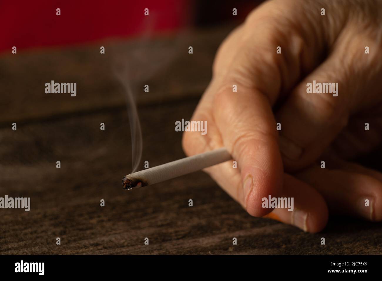 woman holding a cigarette at home at the table, smoking at home in the ...