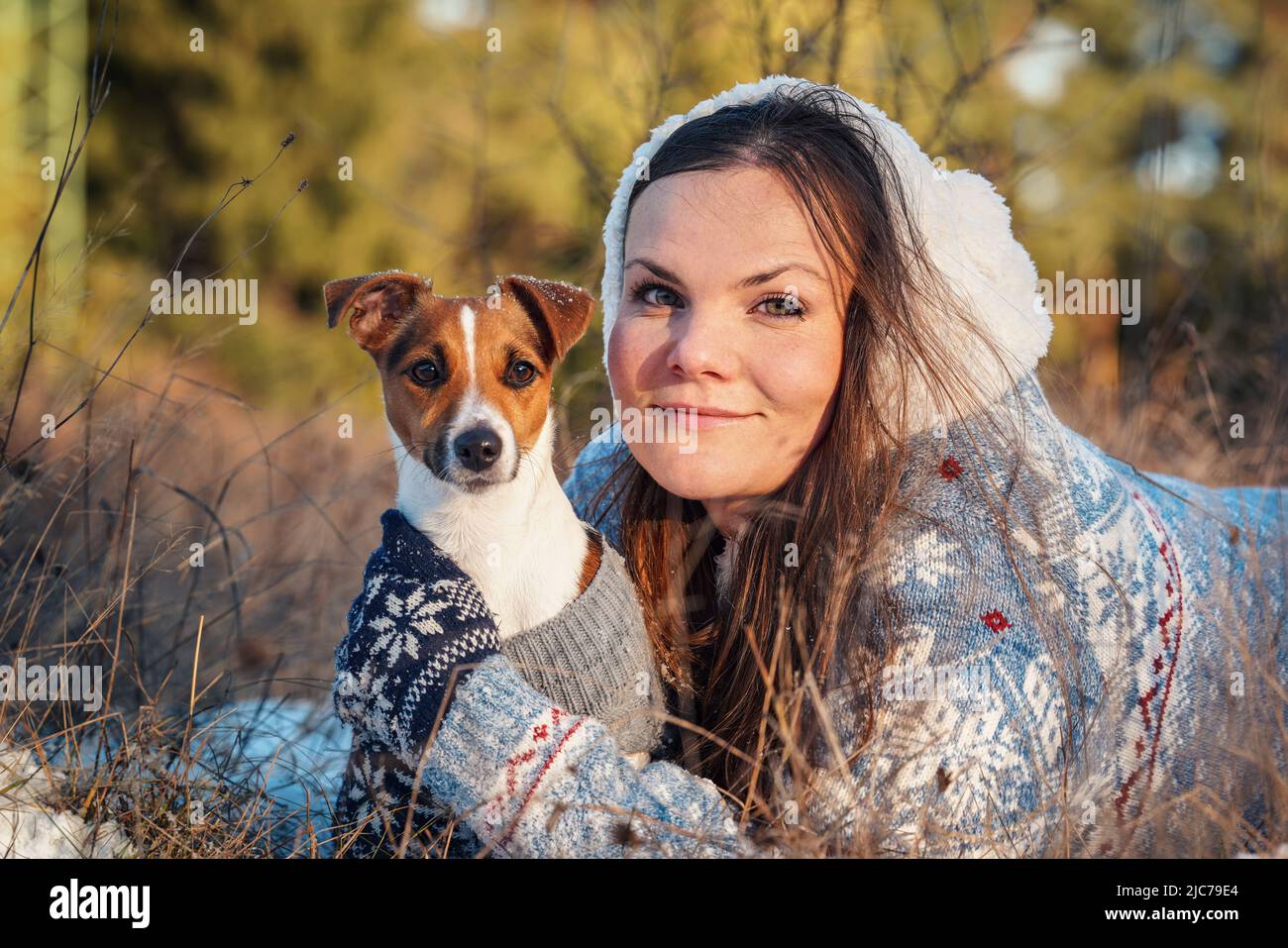 Young woman in winter jacket lying down at snow covered ground, holding ...