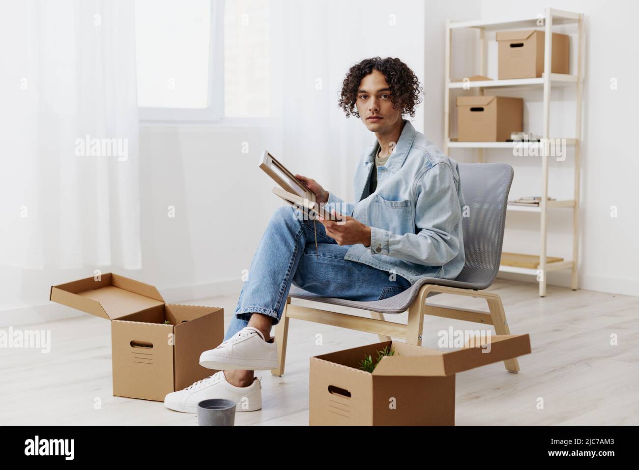 A young man unpacking things from boxes in the room sorting things out ...