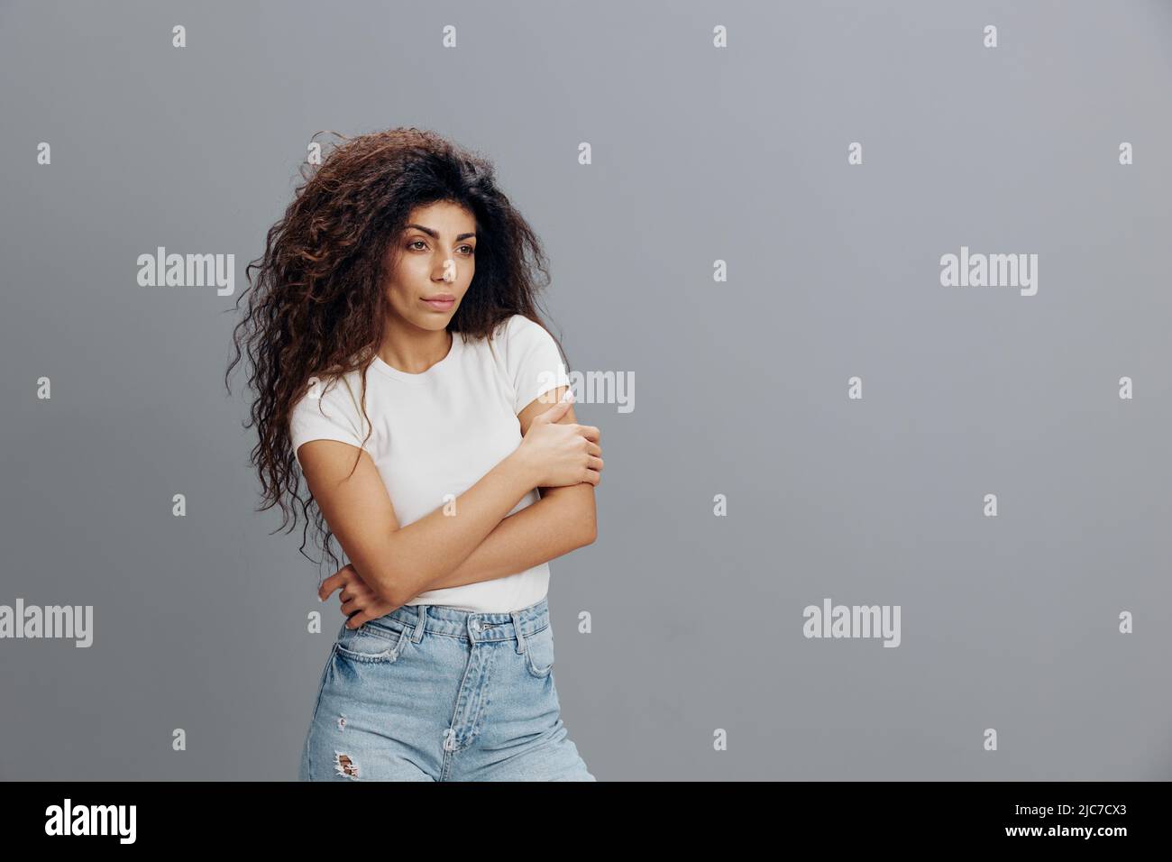 Curly serious smart confident happy caucasian woman 20s wearing white basic shirt hold hand ...