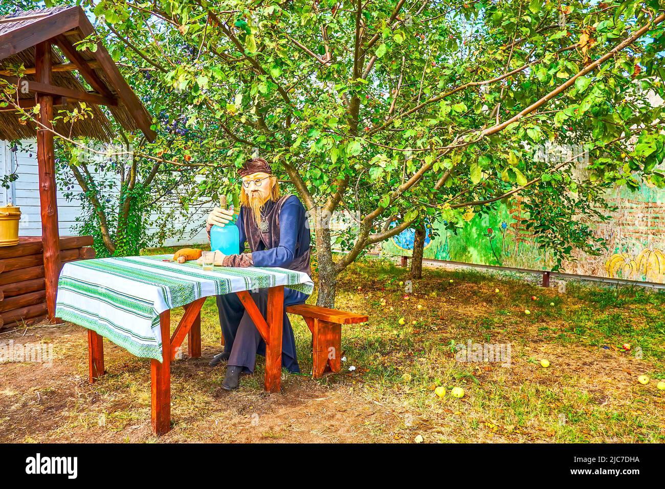 The sculpture of the priest at the table with a bottle of samogon ...