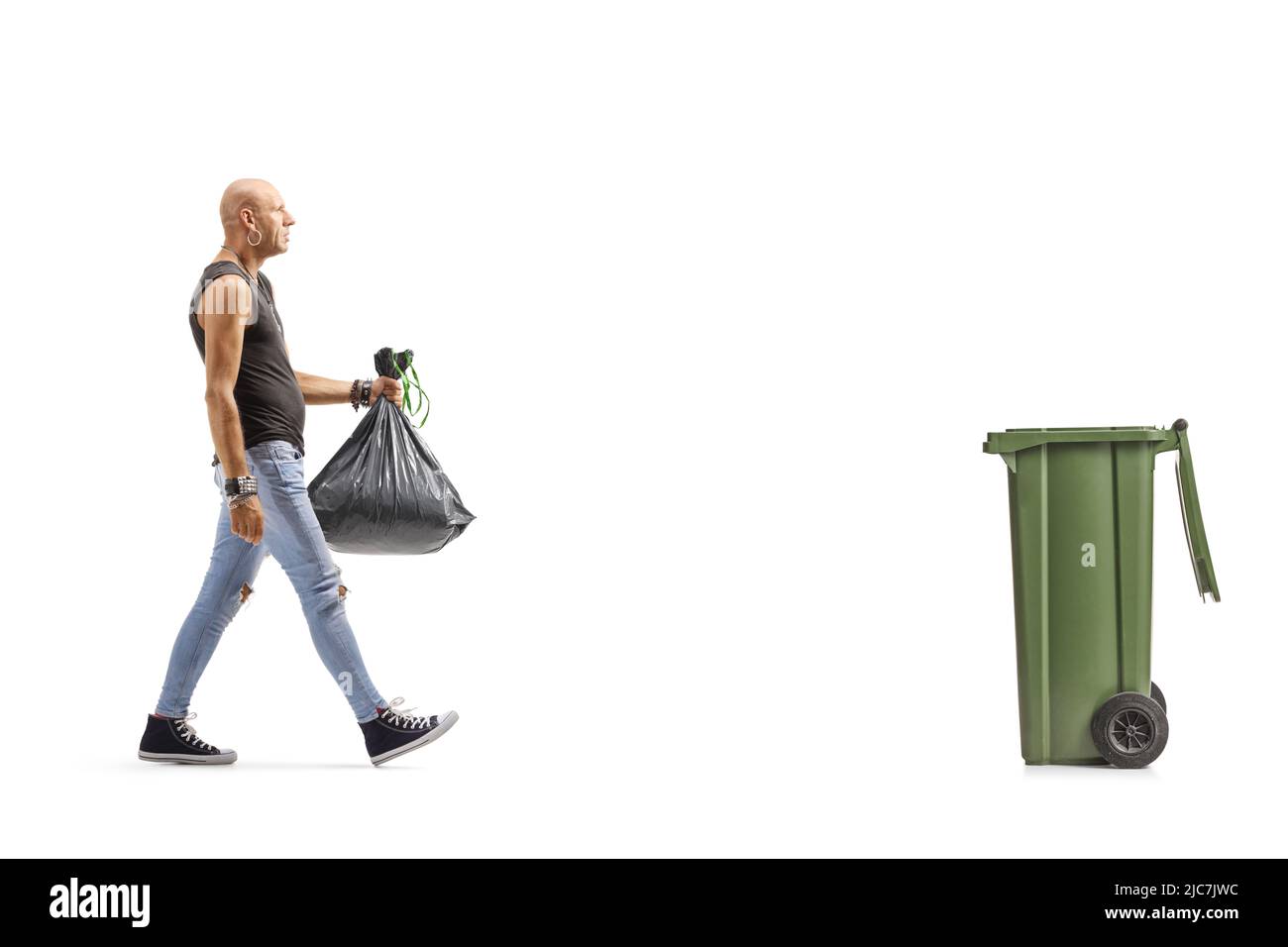 Bald man in ripped jeans carrying a plastic waste bag and walking ...