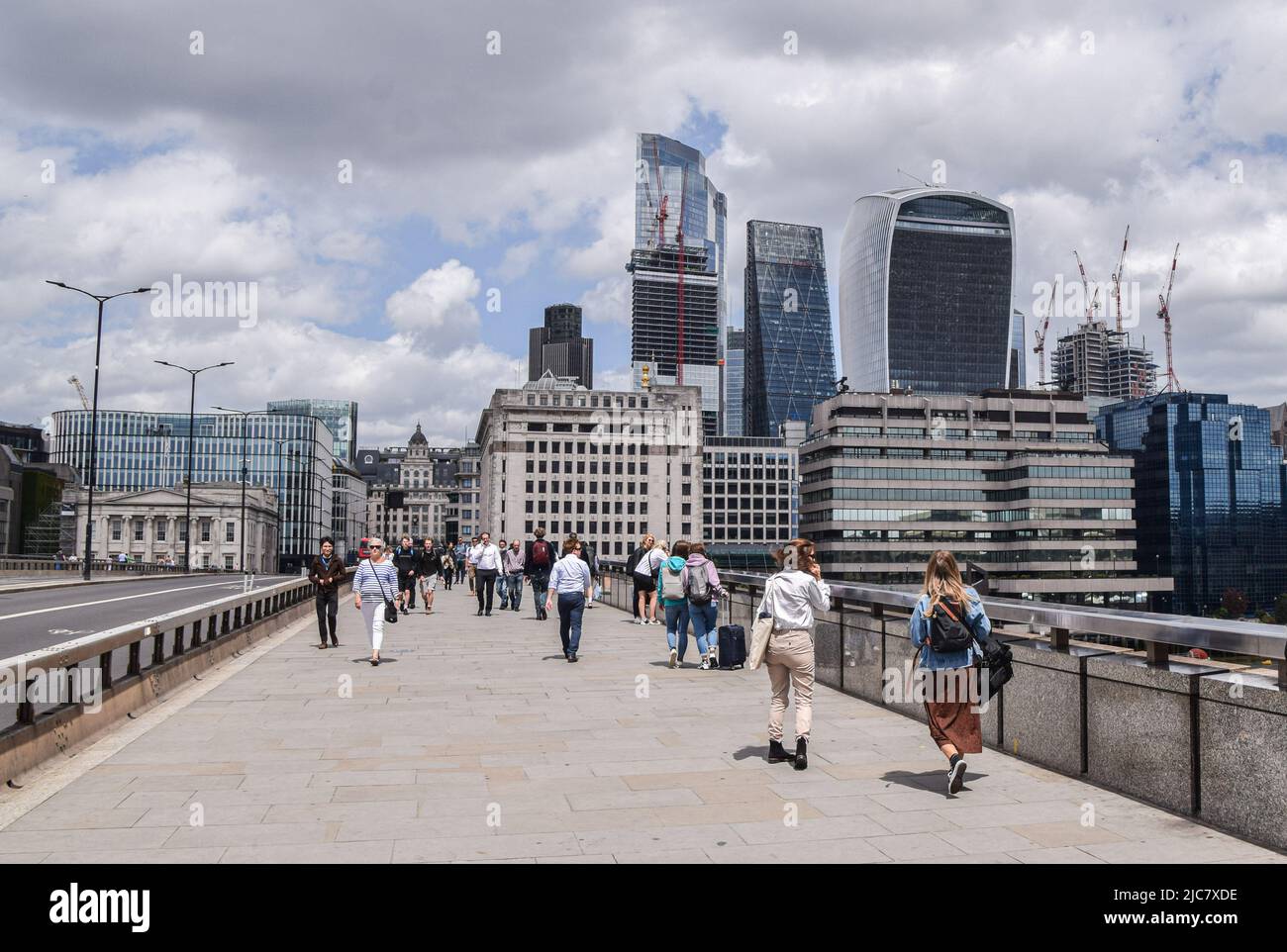 People walk along London Bridge past the City of London skyline, the ...
