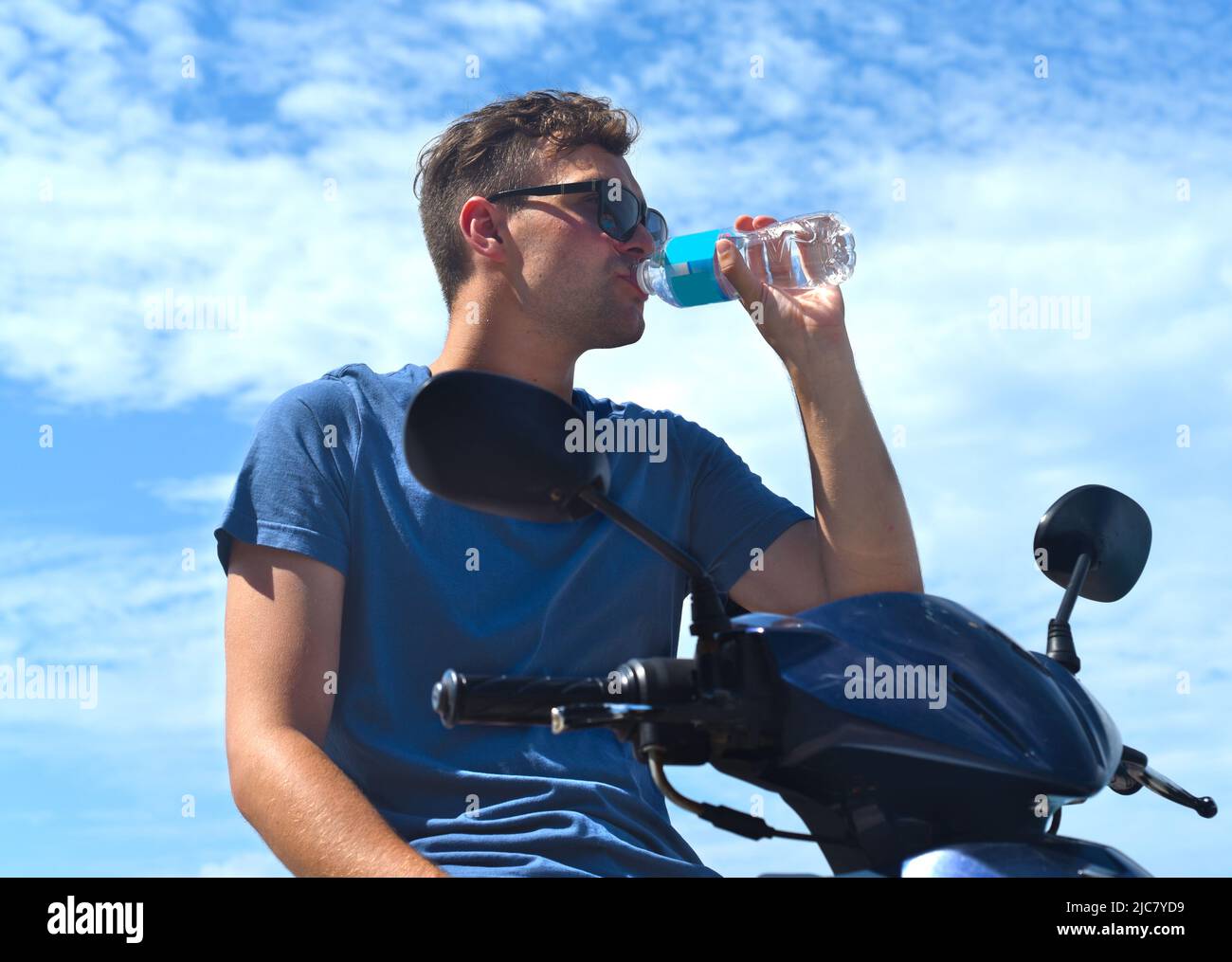 Young man a motorbike driver drinking water from a plastic bottle Stock ...