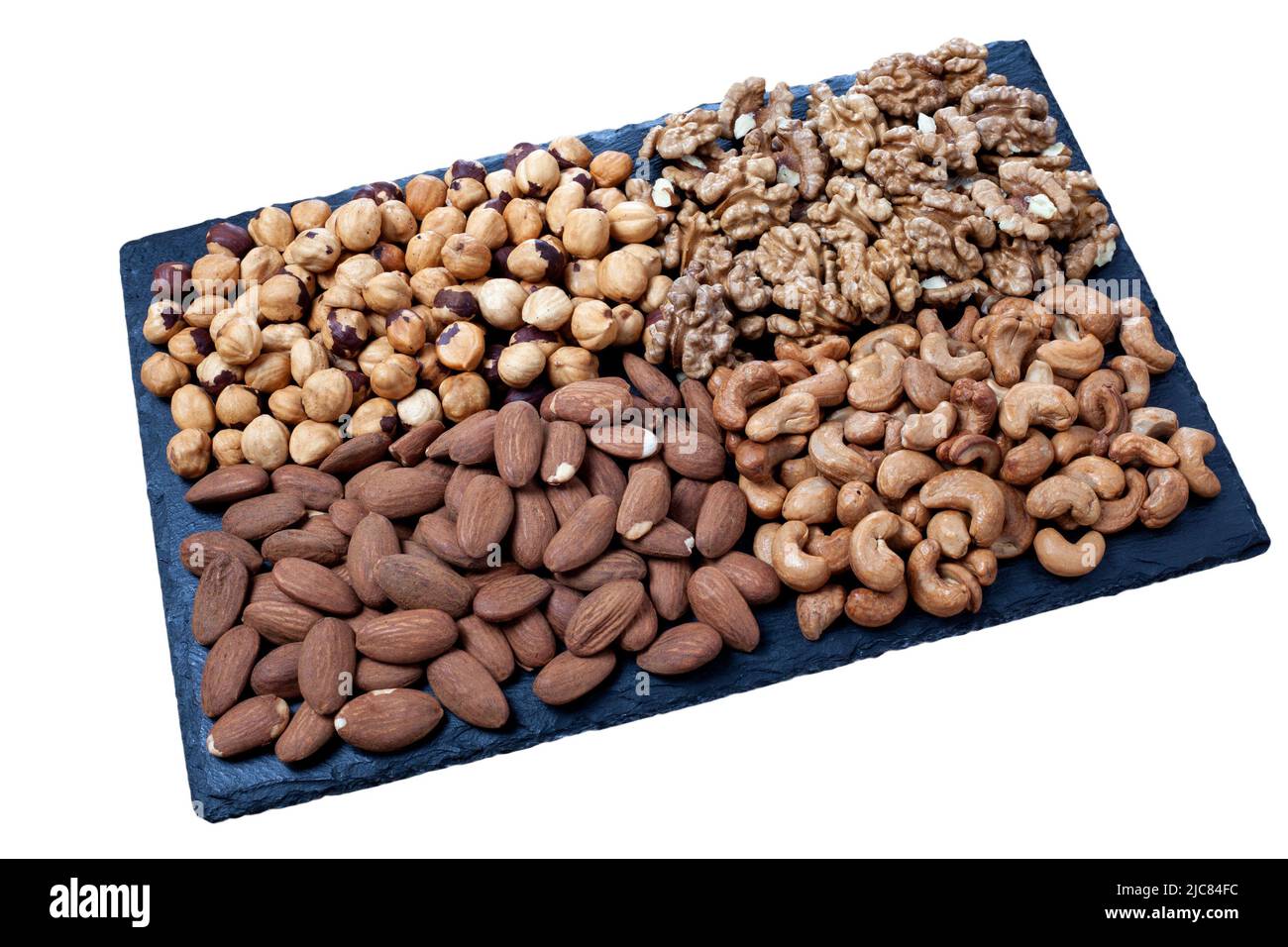Various nuts sorted on black stone plate isolated on white background ...
