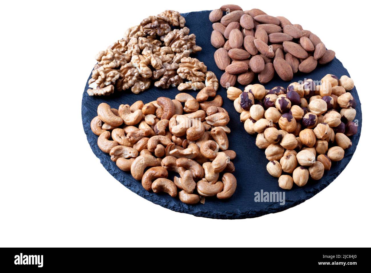Various nuts sorted on black stone plate isolated on white background ...