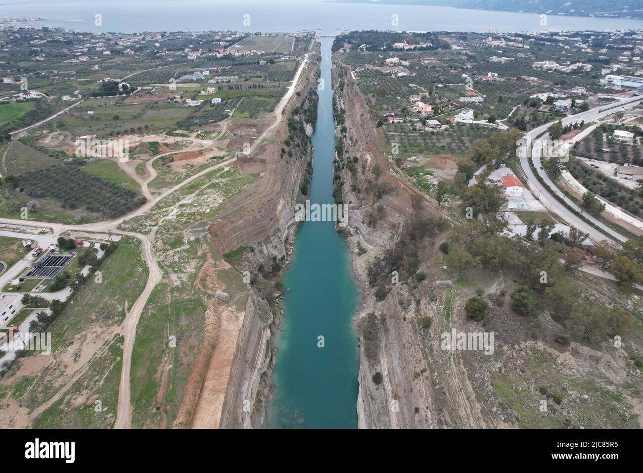 Drone aerial view of the Corinth canal with a bridge across green water ...
