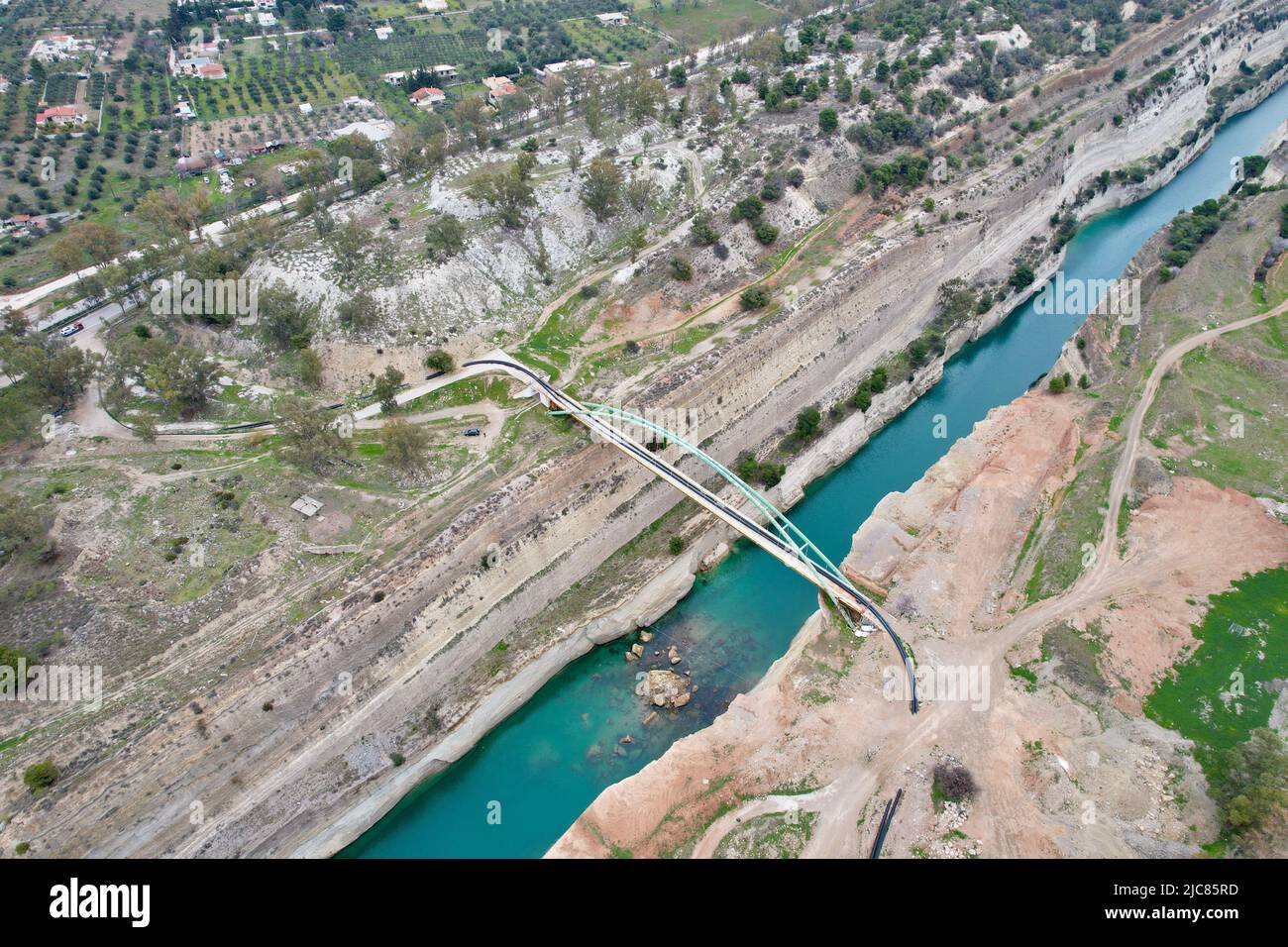Drone aerial view of the Corinth canal with a bridge across green water ...