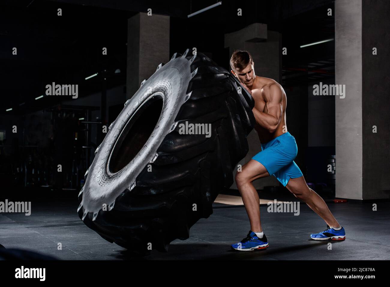 Crossfit training - man flipping tire in gym Stock Photo - Alamy