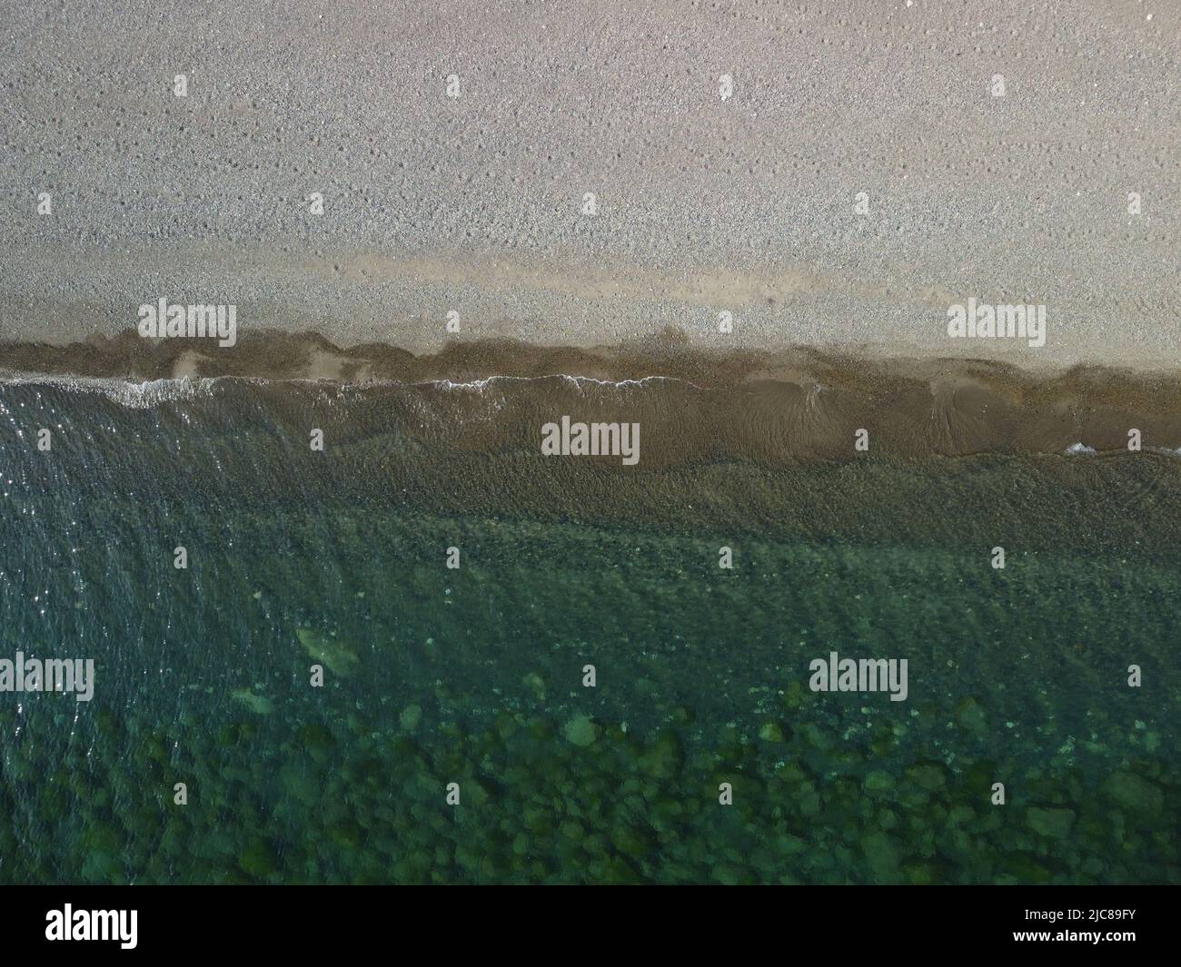 Aerial view on calm azure sea and volcanic rocky shores. Small waves on ...