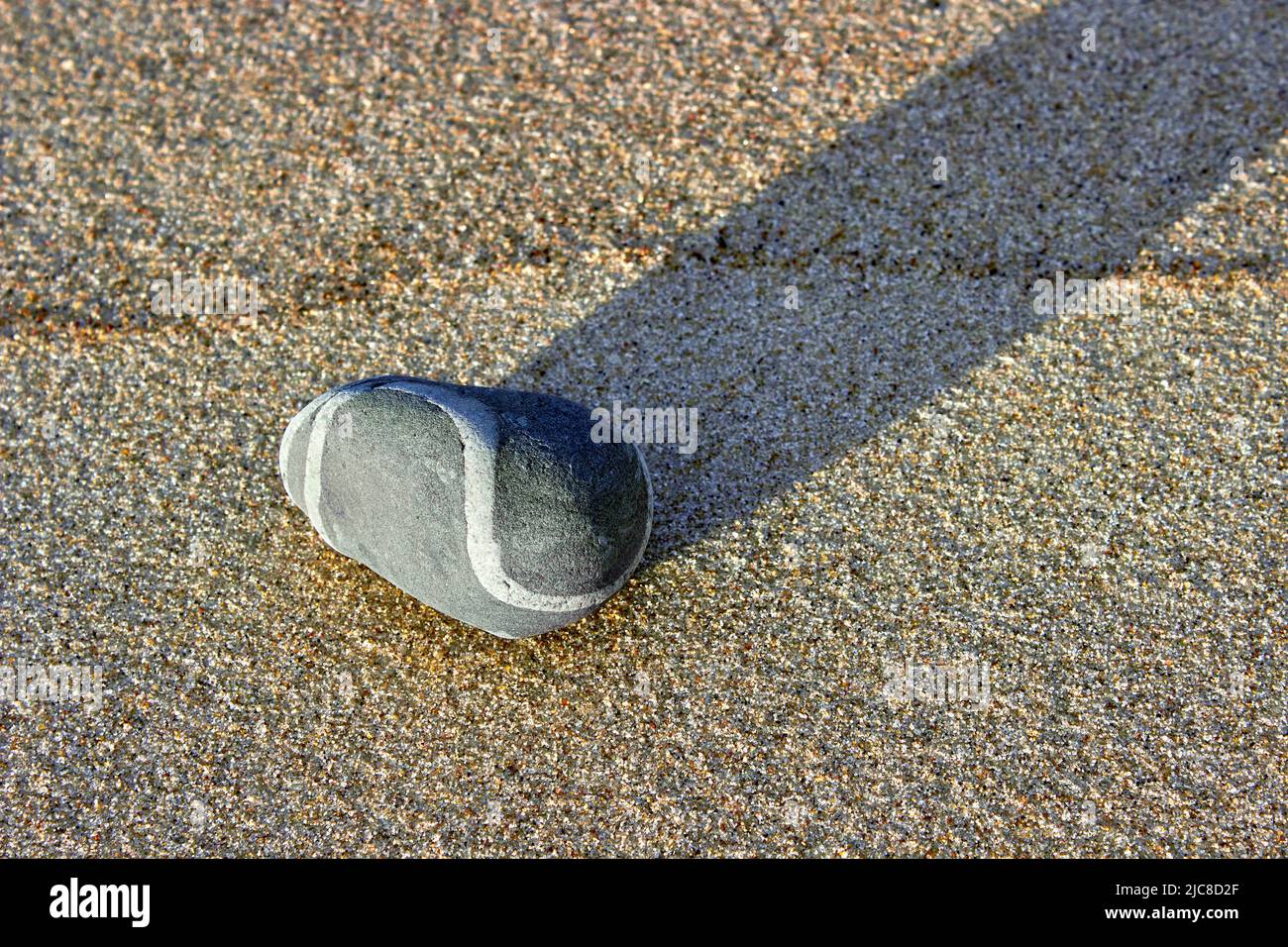 Amazing stone on a sand background. Long shadow Stock Photo - Alamy