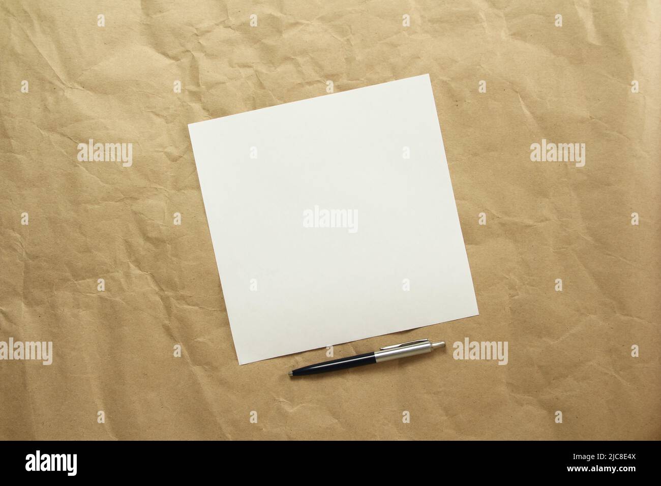 Square white empty sheet of paper with pen on a beige craft paper ...