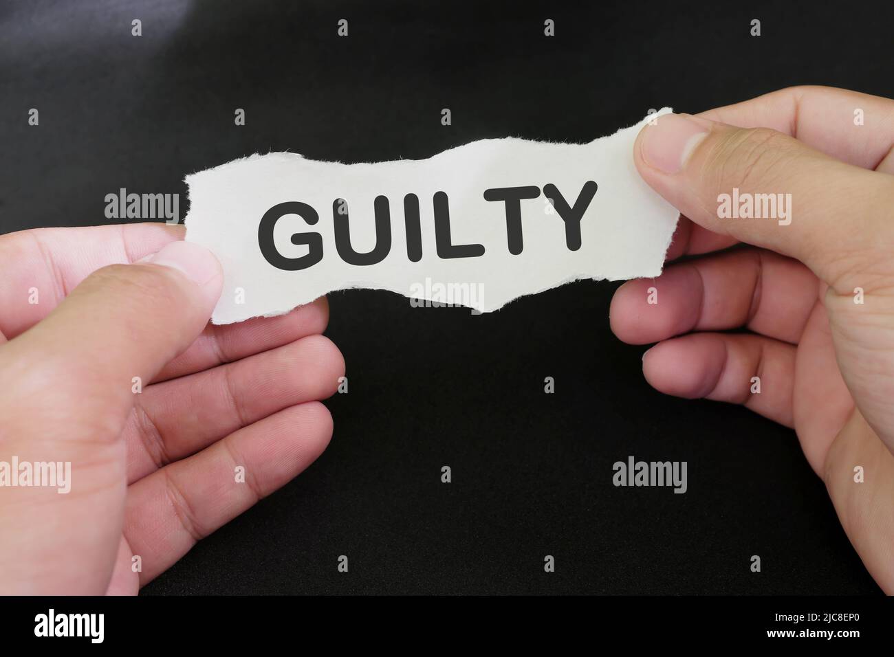 Guilty verdict concept. Hand holding a piece of paper with written word ...