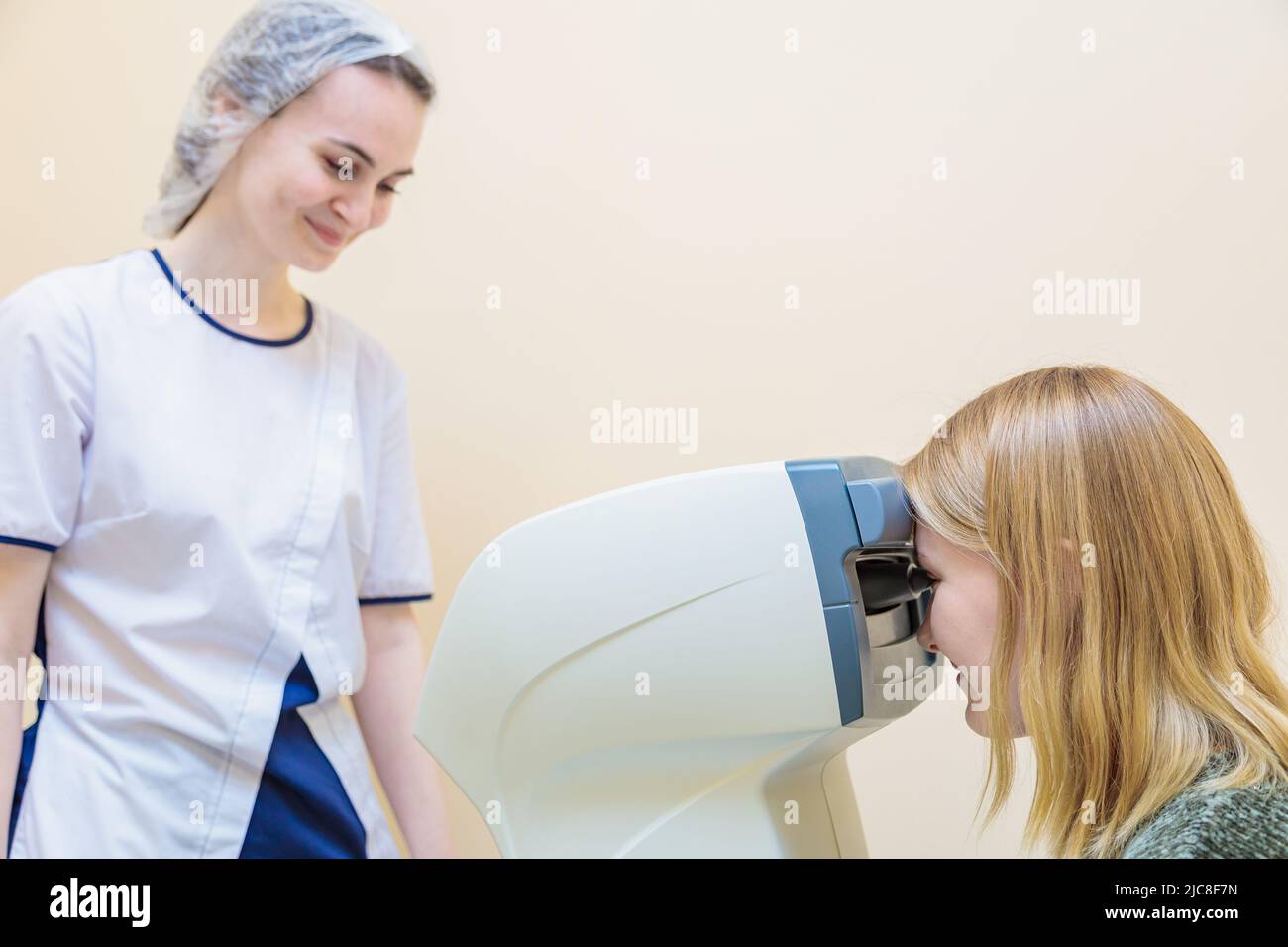 A girl optometrist examines the eyes of a patient using special modern ...