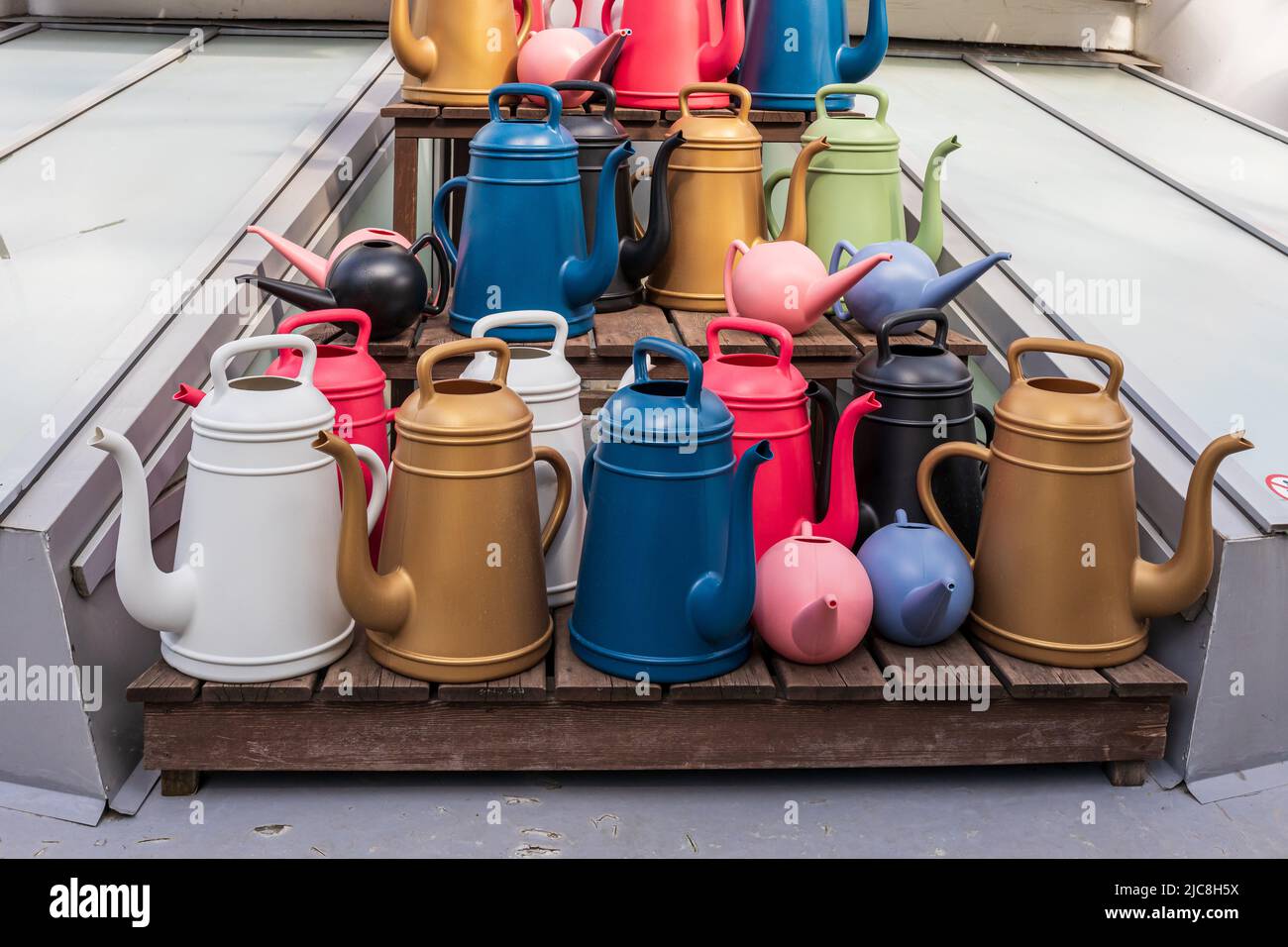Different sizes of different colors of watering cans for sale in a ...