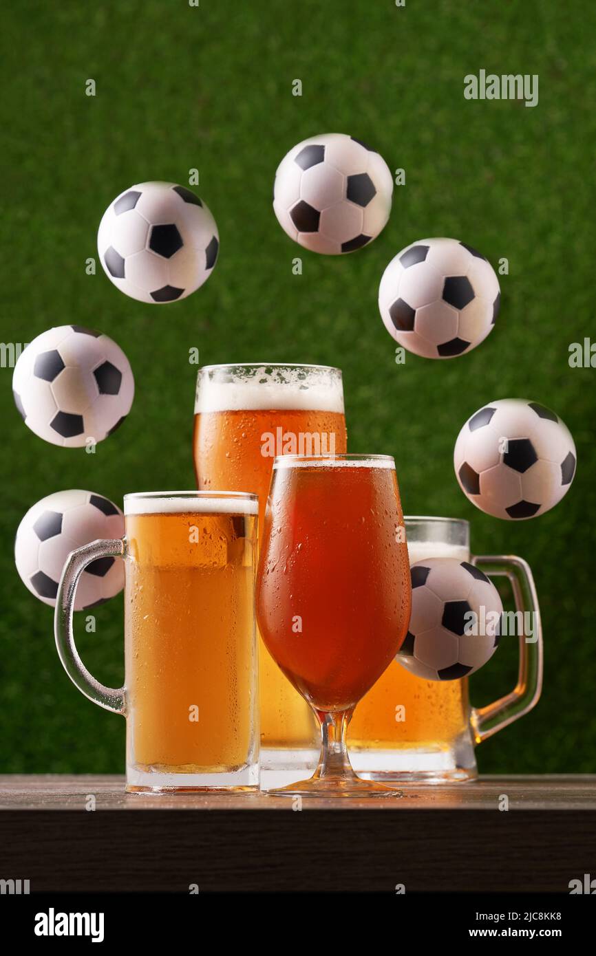 Four glasses of beer with circle frame from soccer balls on the green ...