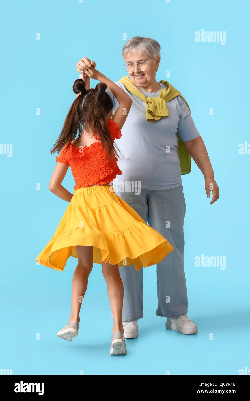 Little girl with her grandma dancing on blue background Stock Photo - Alamy