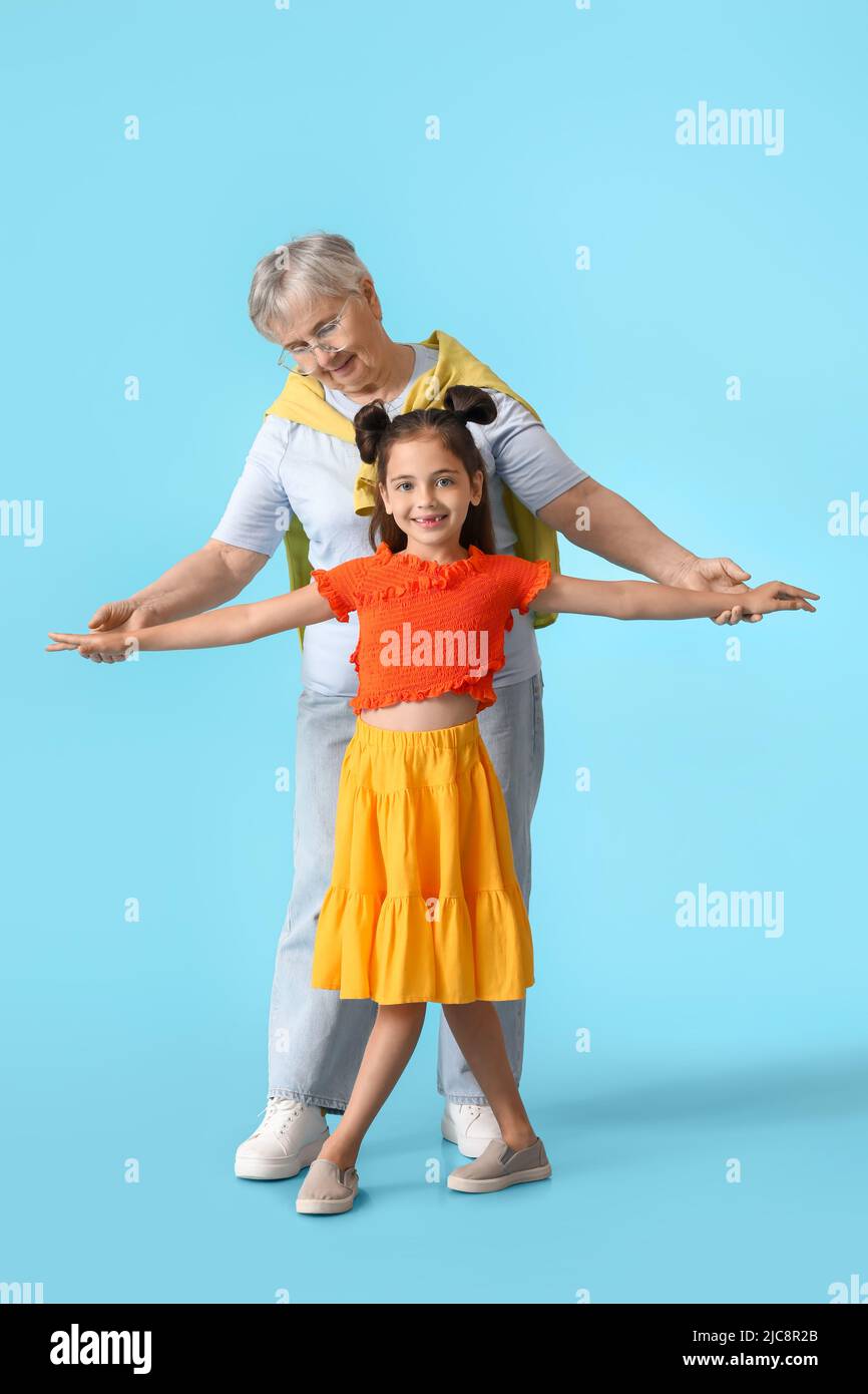 Little girl with her grandma dancing on blue background Stock Photo - Alamy