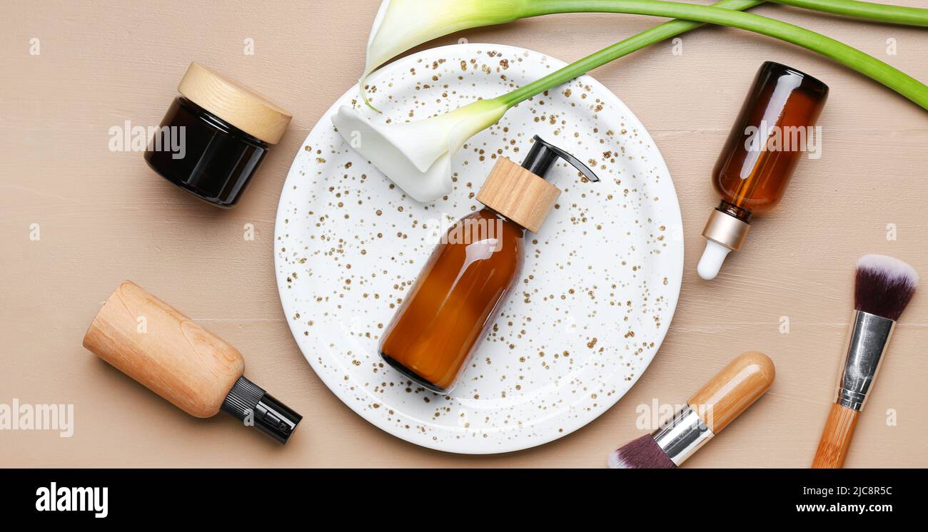 Set of cosmetic products, makeup brushes and calla lilies on color ...