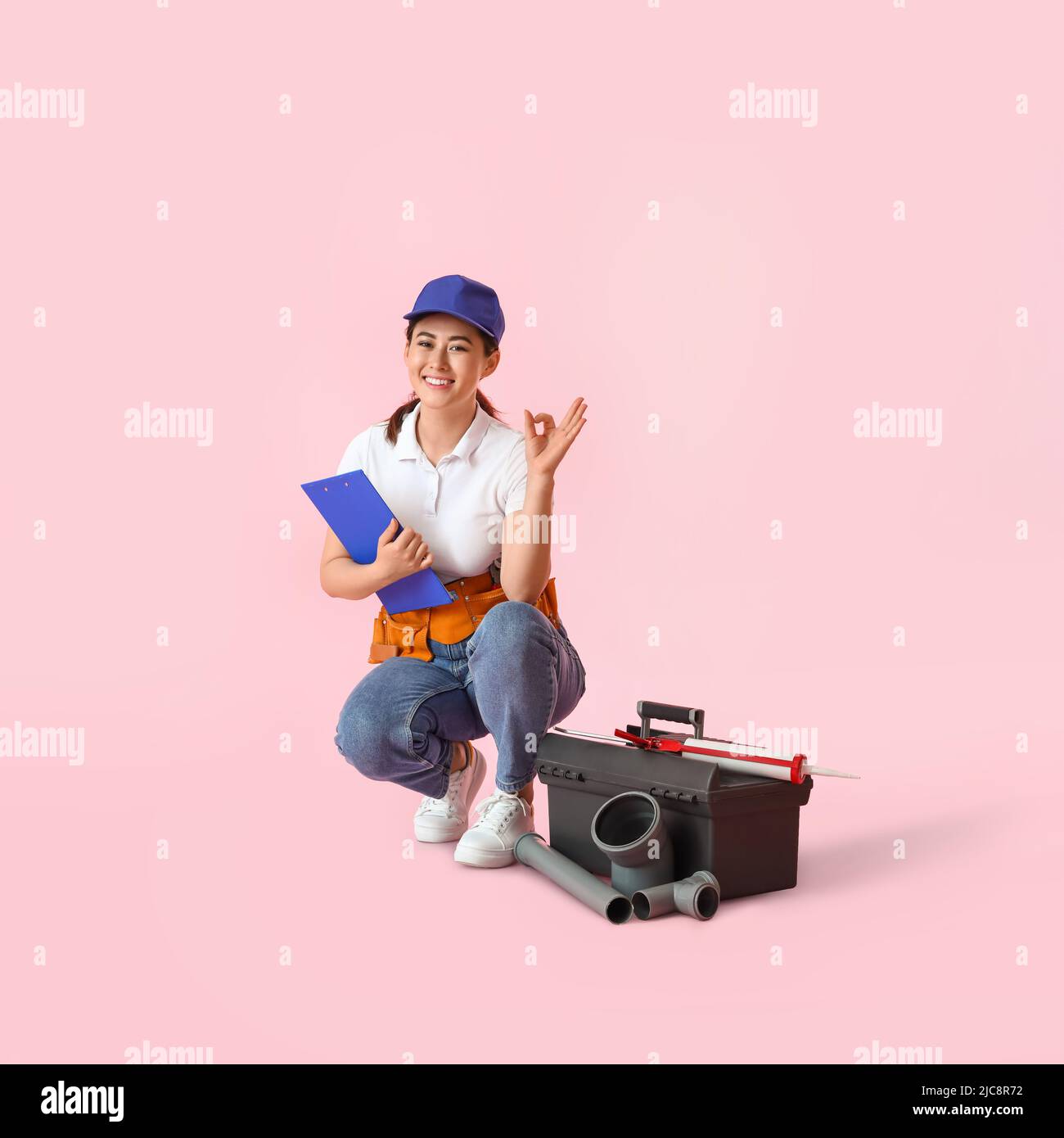 Asian female plumber with clipboard and bag on pink background Stock ...