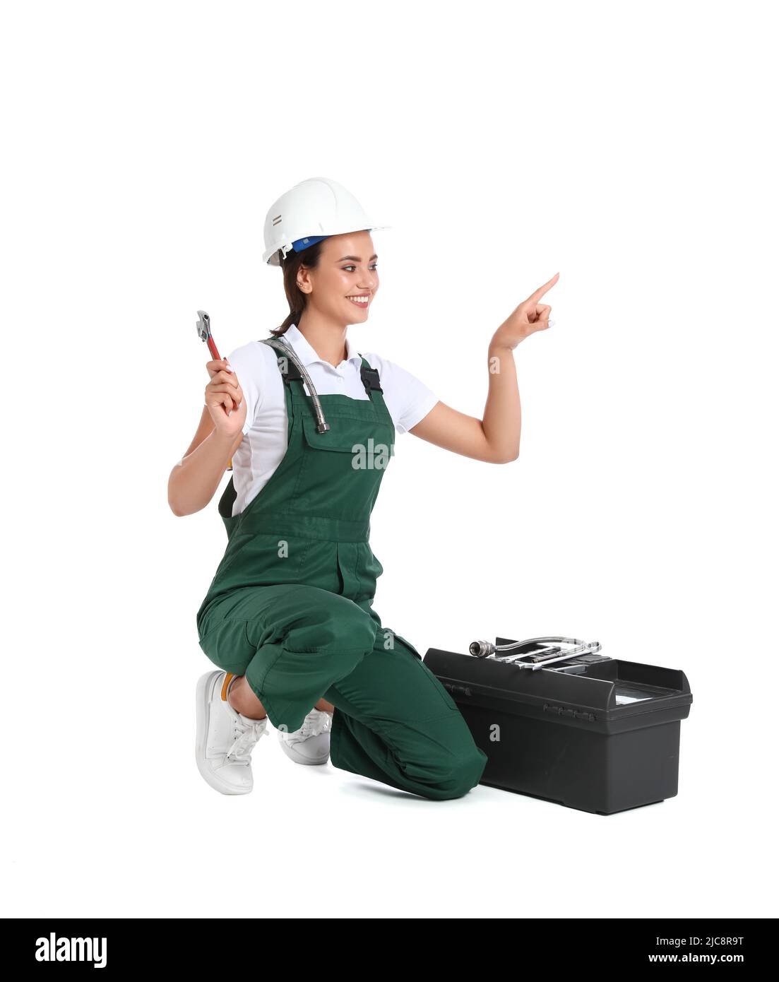 Female plumber with wrench pointing at something on white background ...
