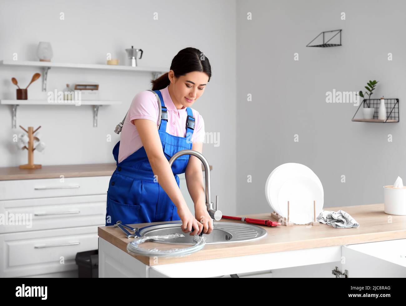 Asian female plumber fixing sink with plunger in kitchen Stock Photo ...
