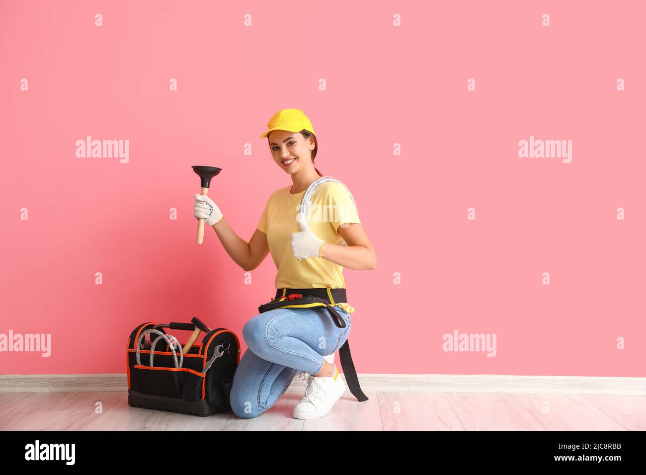 Female plumber with plunger near pink wall Stock Photo - Alamy