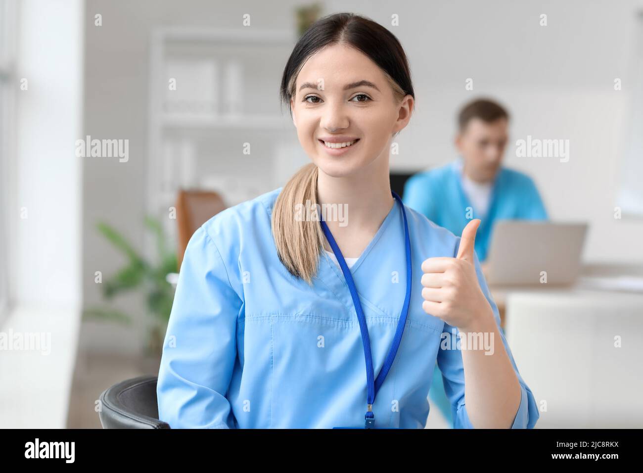 Female medical assistant showing thumb-up at hospital Stock Photo - Alamy