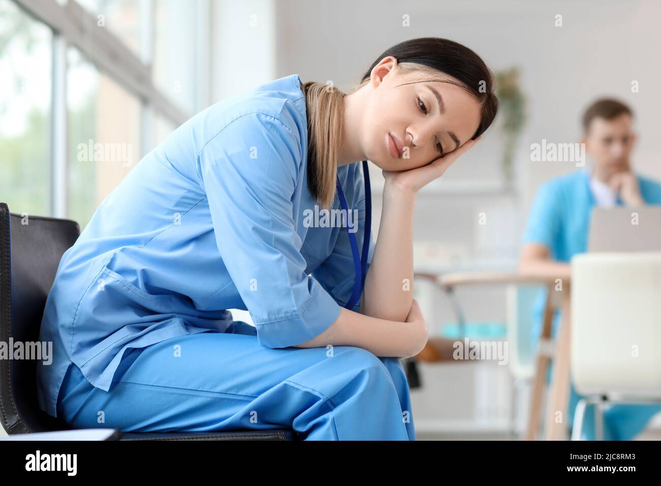 Tired female medical assistant sitting in clinic Stock Photo - Alamy