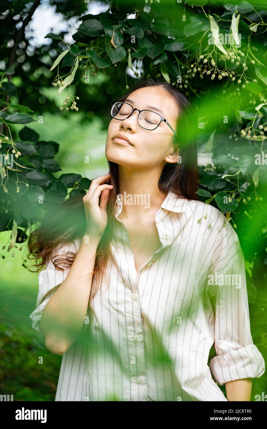 Young Vietnamese woman standing enjoying green fresh tree leaves in ...