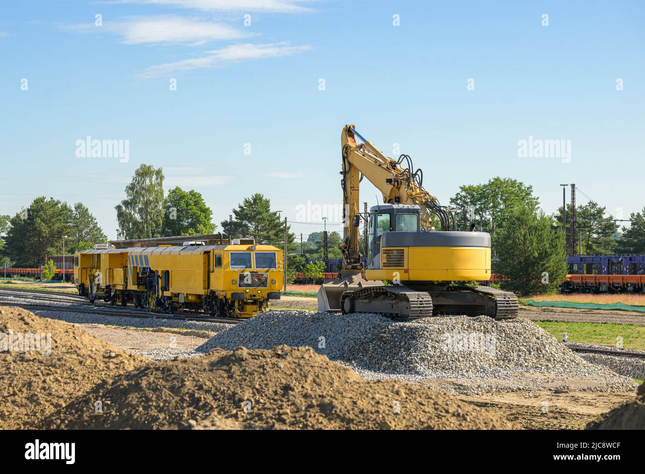 Excavator and track tamping machine on a construction site Stock Photo ...